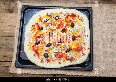 Preparing a pizza putting various ingredients over the dough before ...