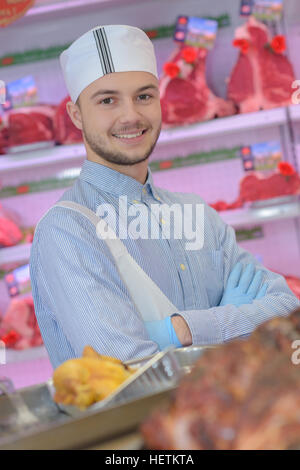 Portrait of male butcher standing with arms crossed at meat factory ...