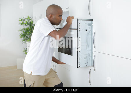 Man fitting new oven Stock Photo - Alamy