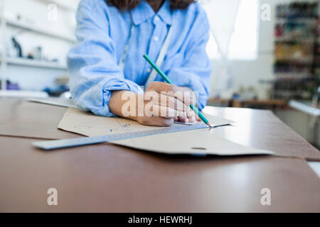 Female seamstress drawing sewing pattern on paper in studio Stock Photo ...