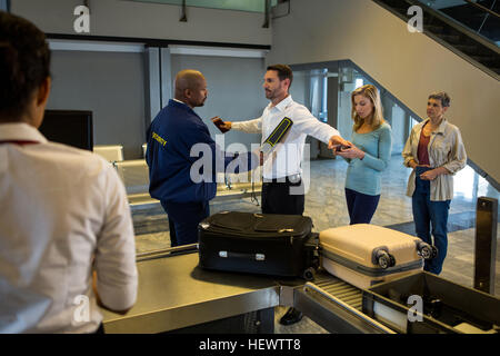 Security guard frisk passengers standing in queue at airport terminal ...