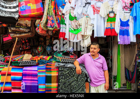 Shopkeeper selling clothing, hats and other souvenirs at a shop on 5th ...