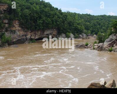 Fast moving muddy water rapids over a weir and falling down splashing ...