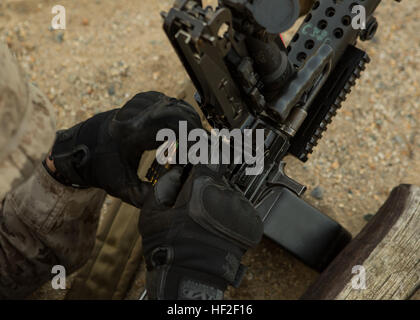 A Marine fires an M-249 squad automatic weapon from a fighting position ...