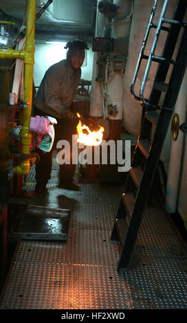A Fireman aboard USS Boxer (LHD 4) prepared a torch to light a boiler ...