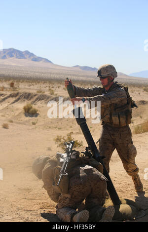 A Marine prepares to drop an 81mm mortar round into an M252 medium ...