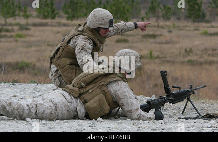 A Marine fires an M-249 squad automatic weapon from a fighting position ...