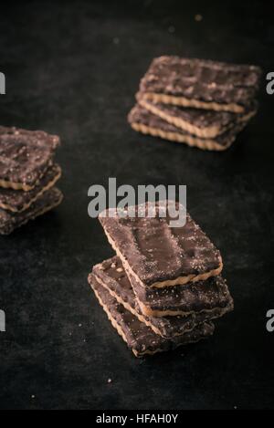 Vertical photo with few stacks of square biscuits with chocolate on one ...