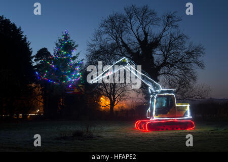 Excavator and Christmas tree with lights decoration at night. Adderbury ...