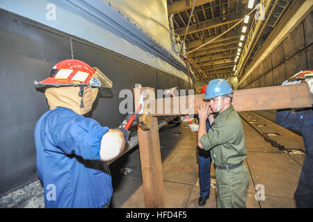 Sailors remove shoring from the well deck of the amphibious assault ...