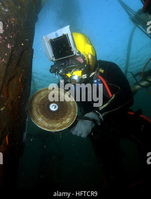 U.S. Navy Diver uses a grinder to file down a repair patch on the ...
