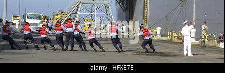 US Navy Line handlers haul the brow of the amphibious assault ship USS ...
