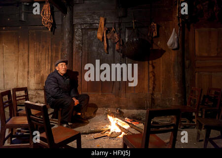 A lonely old Chinese man sits in the shade on flies of stairs outside ...