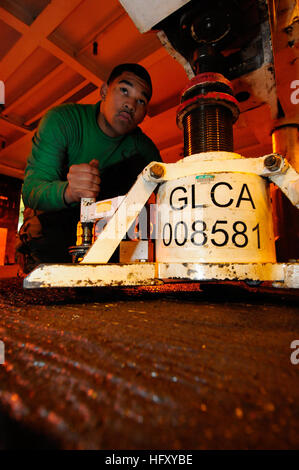 US Navy Airman pulls a new arresting gear cable out onto the hangar bay ...