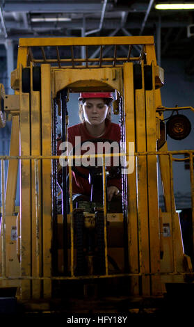 US Navy A Sailor drives his forklift loaded with cargo onto the ...