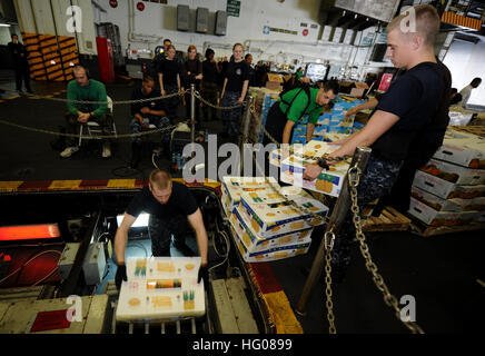 US Navy Sailors send stores down to a storeroom from hangar bay three ...