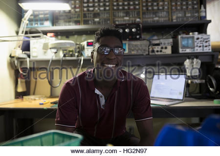 Portrait smiling male electronics engineer at workbench in workshop ...