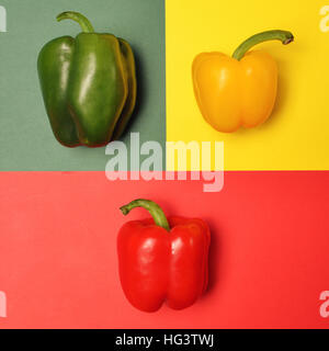 Three colorful paprikas on yellow background - Minimal flat lay view ...