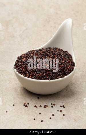 quinoa seeds in bowl and spoon on colored background. Healthy kinwa in ...