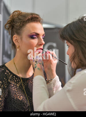 Unrecognized woman cosmetologist demonstrates makeup blending skills at ...