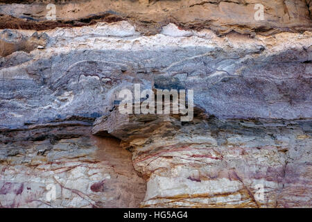 A magmatic dike cross-cutting horizontal layers of color bands in a ...