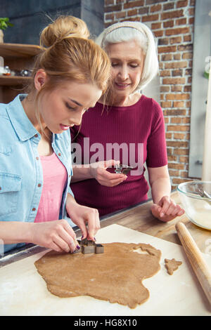 Grandmother and her granddaughter making cookies together at table in ...
