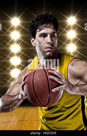 Basketball player on a yellow uniform, on a yellow lights background ...