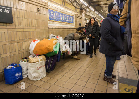 A homeless individual sleeps on a bench in a subway station in New York ...