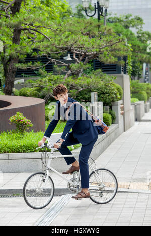 Young businessman with crossbody bag riding electric push scooter on ...