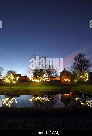 Christmas lights around the village pond on the green in Foolow, PEak ...