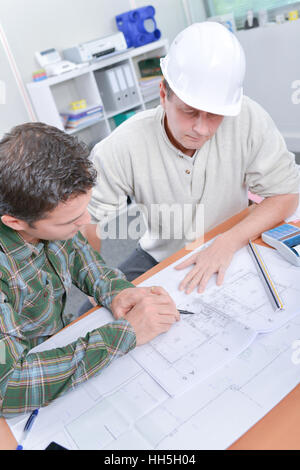 Two men at desk looking at blueprints Stock Photo - Alamy