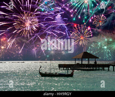 Festive fireworks over the sea and a boat silhouette on water. Maldives ...