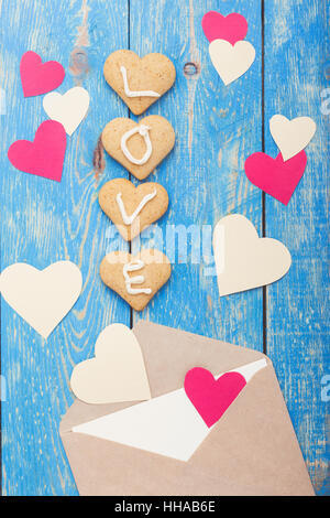 Heart shape cookie and festive paper hearts shaped cards on pink ...