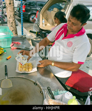 Man is cooking Thai sweet street food stir fried ice cream rolls from ...