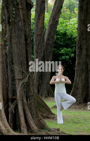 young woman doing yoga under trees Stock Photo - Alamy