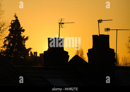 Sun setting over silhouetted rooftops Stock Photo - Alamy