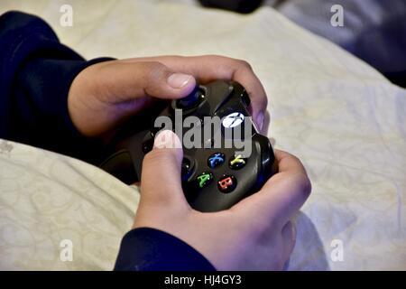 A young teen holding an Xbox One controller while playing Xbox games ...