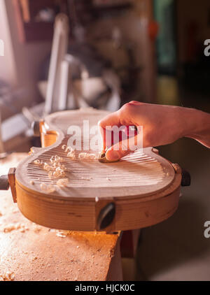 hands of artisan woman violin maker luthier working in the back table ...