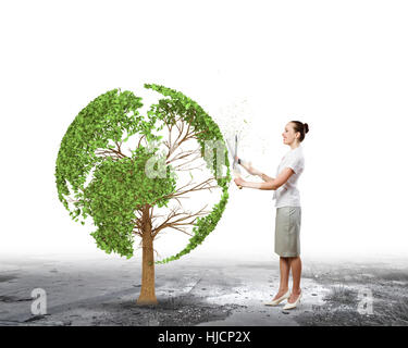 Young businesswoman cutting tree with scissors in shape of Earth planet ...