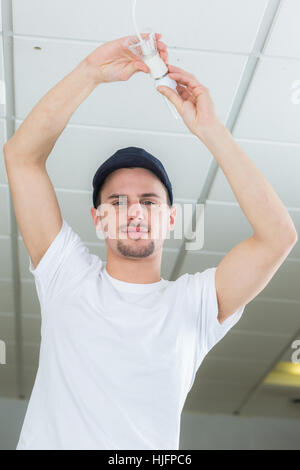 Happy male electrician changing light bulb in floor lamp at home Stock ...