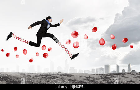 Businessman in suit jumping with big springs on feet Stock Photo - Alamy