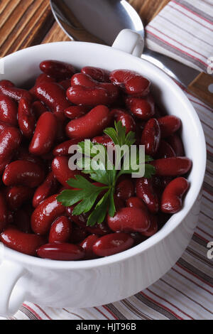 Cooked red kidney beans in a dark ceramic bowl on a rustic wooden table ...