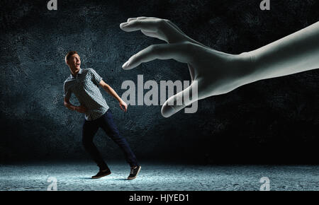 Funny image of young man trying to escape from huge hand Stock Photo ...