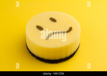 dish washing concept yellow sponge with sad face on a dining white ...