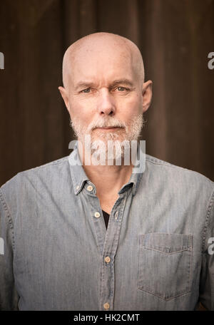 Portrait of a pensive determined senior man standing leaning against a ...