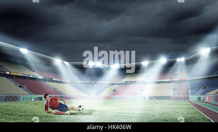 Football player at stadium sliding to kick the ball Stock Photo - Alamy