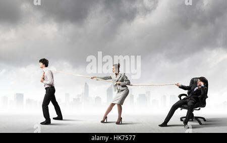 Image of three businesspeople pulling rope against city background ...