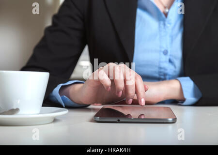 Female manager types on tablet pc screen while she has a coffee break ...