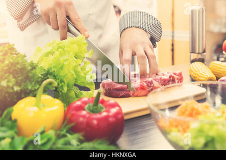 Chef cutting meat on wooden board. Butcher hands close up cutting meet ...