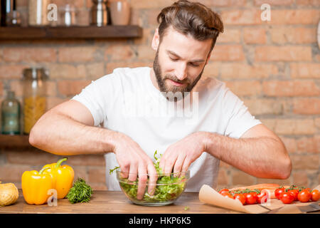 Young man making a salad Stock Photo - Alamy